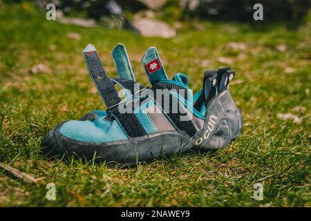 A close up of dirty-blue Ocun Strike LU Climbing shoes on a grass field ...