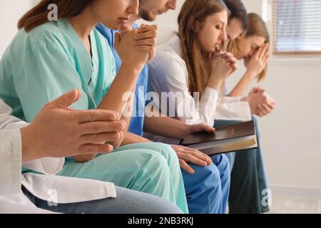 Group of doctors praying with Holy Bible in clinic, closeup Stock Photo ...