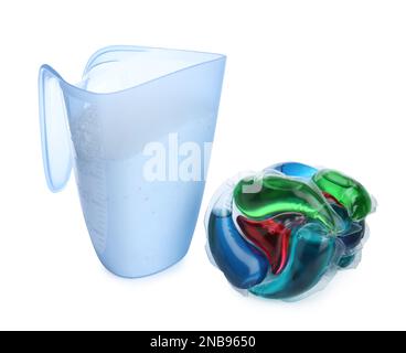 Laundry capsules and measuring cup of washing powder on white ...