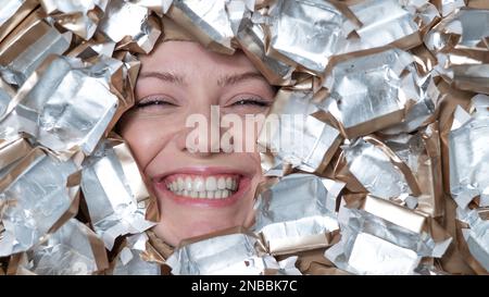 The face of a Caucasian woman surrounded by candy wrappers Stock Photo ...