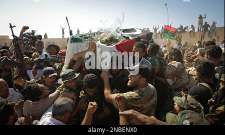 Libyan men carry the coffin, gesture and chant slogans during funeral ...