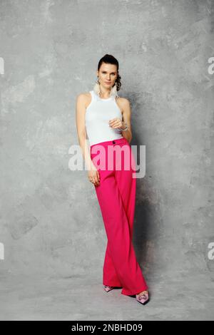 Beautiful woman standing over pink background sticking tongue out happy ...