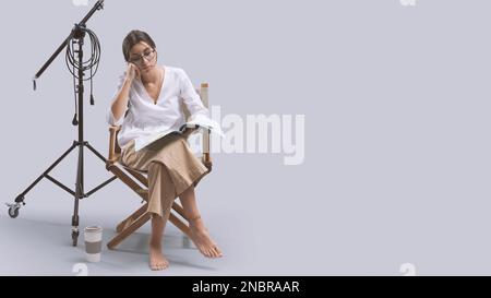 Focused actress sitting on the director's chair and reading a play ...
