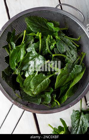 Colander with fresh spinach on table Stock Photo - Alamy