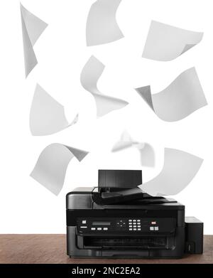 Modern multifunction printer on table and flying sheets of paper ...