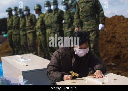 A Japanese mourner touches the coffin for a loved one during a mass ...