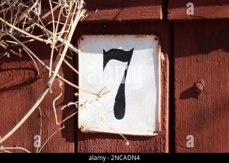 metallic black number seven 7 on white background on a red wooden wall ...