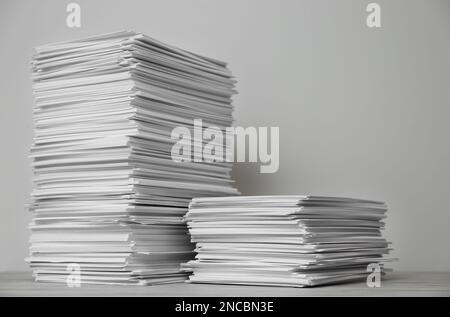 Stacks of paper sheets on wooden table against white background Stock ...