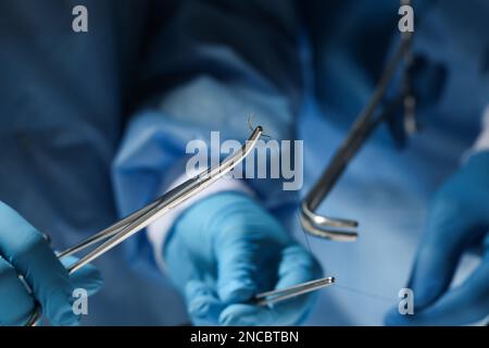 Professional surgeons with forceps and suture thread on blurred ...