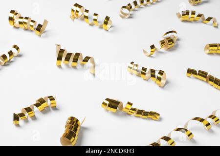 Shiny golden serpentine streamers on black background. Space for text ...