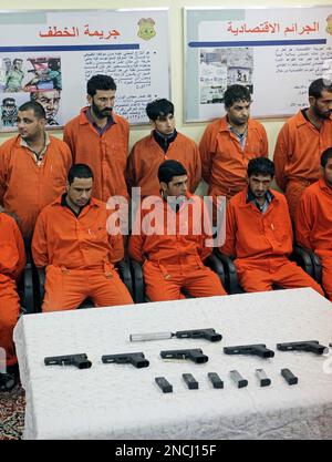 Handcuffed suspected terrorist are seen next to their weapons in the ...
