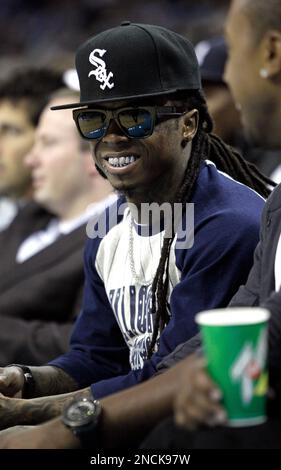 Rapper Lil Wayne sits courtside during an NBA basketball game between ...
