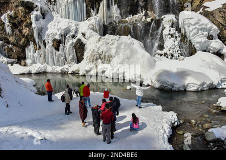 Visitors explore the frozen Drung waterfall on a sunny winter day in ...