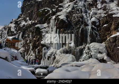 Visitors explore the frozen Drung waterfall on a sunny winter day in ...