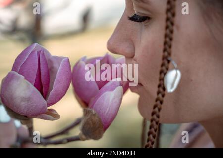 Magnolia flowers, a girl smells a blooming magnolia in the park in the ...