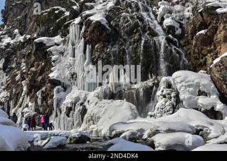 Visitors explore the frozen Drung waterfall on a sunny winter day in ...