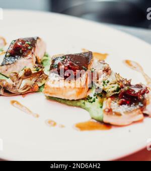 A tasty hake loin in green sauce on a white plate. Fish and healthy ...