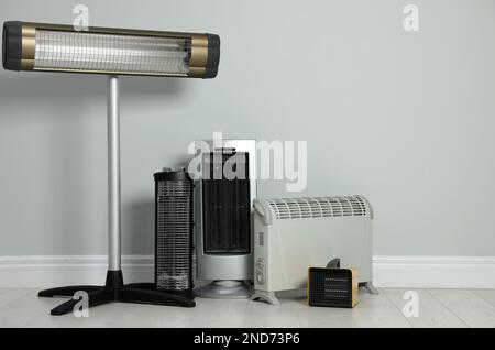 Different electric heaters near light grey wall indoors Stock Photo - Alamy