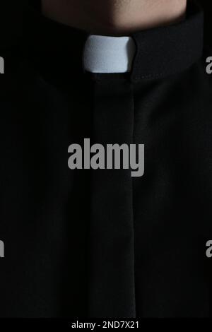 Catholic priest wearing traditional clerical collar shirt sitting with ...