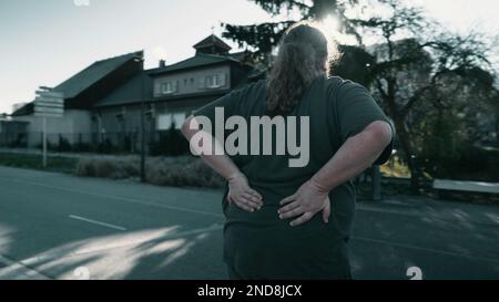 Dramatic moment of person suffering from back pain. An overweight man ...