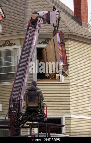 Workers using crane to load drywall through second story window of ...