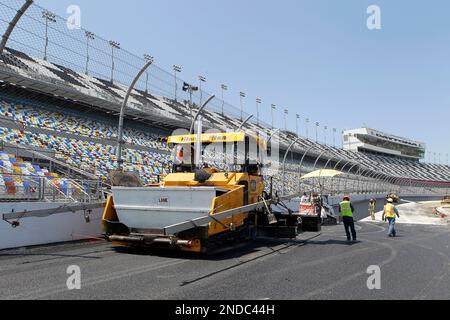 Paving equipment puts a layer of asphalt on the track surface during a ...