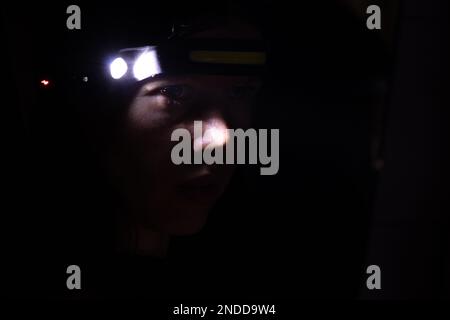 A girl with a headlamp shines in the dark, the light of a lantern Stock ...