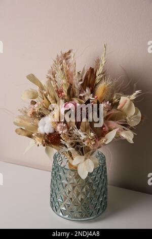 Table with protea flowers near light wall in room Stock Photo - Alamy