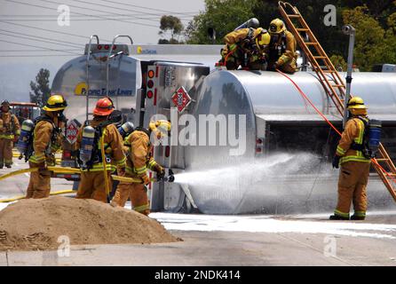 Firefighters spray foam on a gasoline tanker truck that overturned in a ...