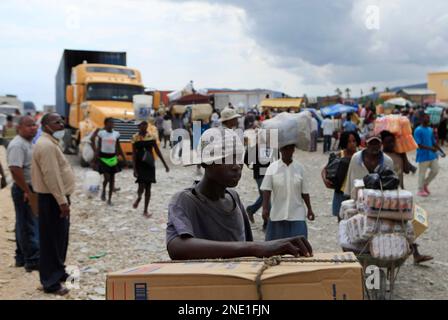 People carry items into Haiti from the Dominican Republic in Malpasse ...