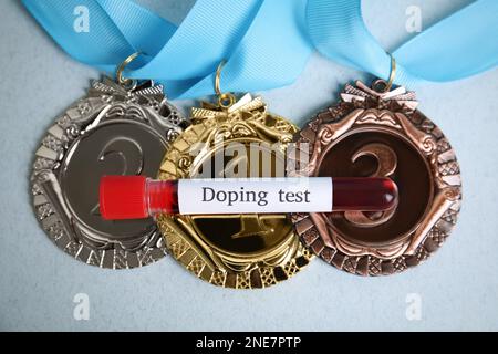 Medals and tube of blood with words Doping test on grey stone table ...