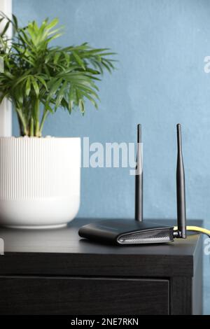 Modern wi-fi router and houseplant on wooden rack indoors Stock Photo ...