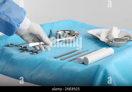 Doctor holding forceps over table with surgical instruments against ...