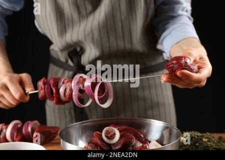 Woman stringing marinated meat on skewer at wooden table, closeup Stock ...