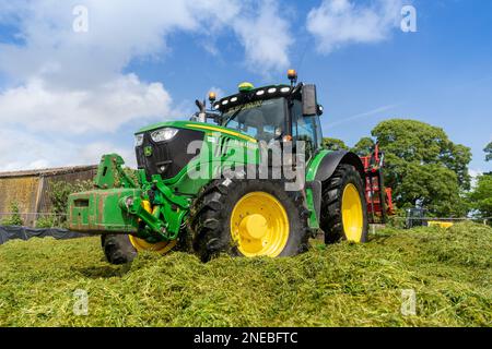 John Deere 6215R with a rear mounted buckrake working on a silage pit ...