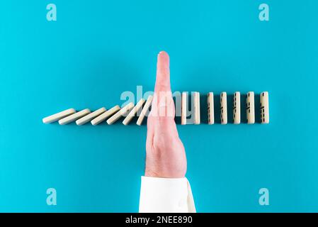 top view of male hand preventing line of domino tiles from toppling and ...