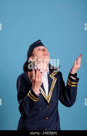 Flight attendant in uniform begging, praying to gods, looking upwards ...