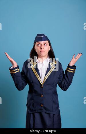 Young confused flight attendant shrugging shoulders, showing unsure ...