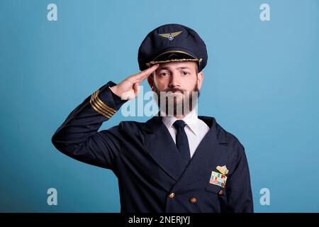 Confident airplane aviator saluting, wearing uniform and hat front view ...