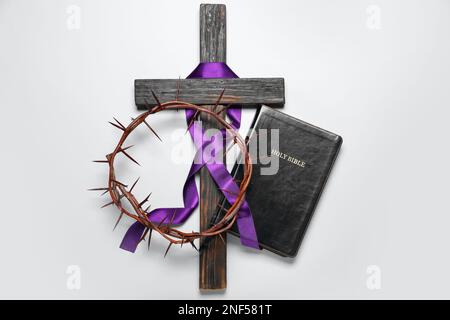 Wooden cross with purple ribbon, crown of thorns and Holy Bible on ...