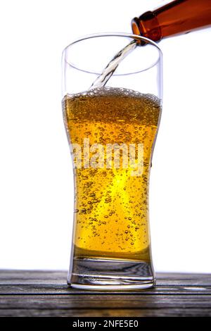 Closeup pour dark beer from brown bottle into glass on black background ...