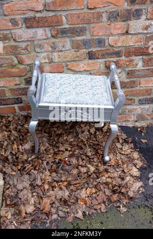 Abandoned silver stool against a red brick wall Stock Photo - Alamy