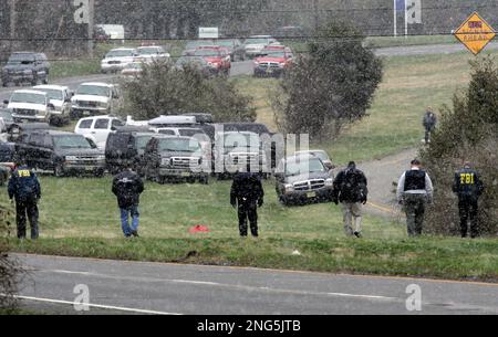 FBI agents walk in a line in a snow squall, as they look for evidence ...