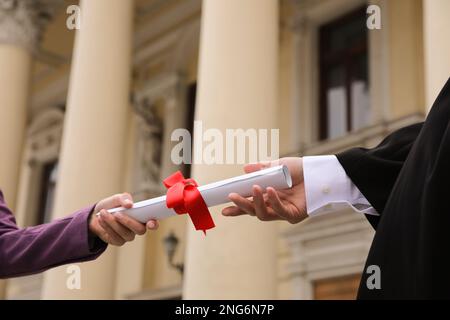 Student receiving diploma during graduation ceremony outdoors, closeup ...