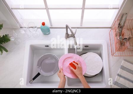 Woman washing plate above sink in modern kitchen, top view Stock Photo ...