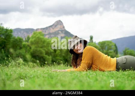 A woman lying in a field of grass with her legs raised against the ...