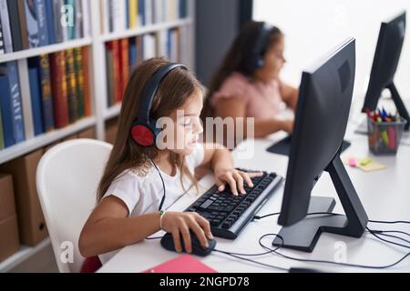 Adorable hispanic boy student using laptop with cheerful expression at ...