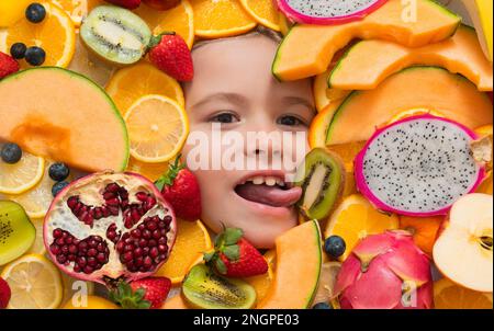 Kid tasting fruits. Kid licking kiwi. Frutit and child face close up ...