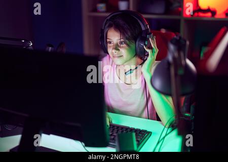 Adorable hispanic girl streamer playing video game using computer at ...
