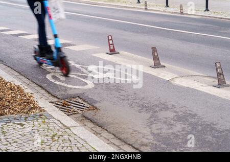 A person travels along a long road surrounded by trees during summer ...